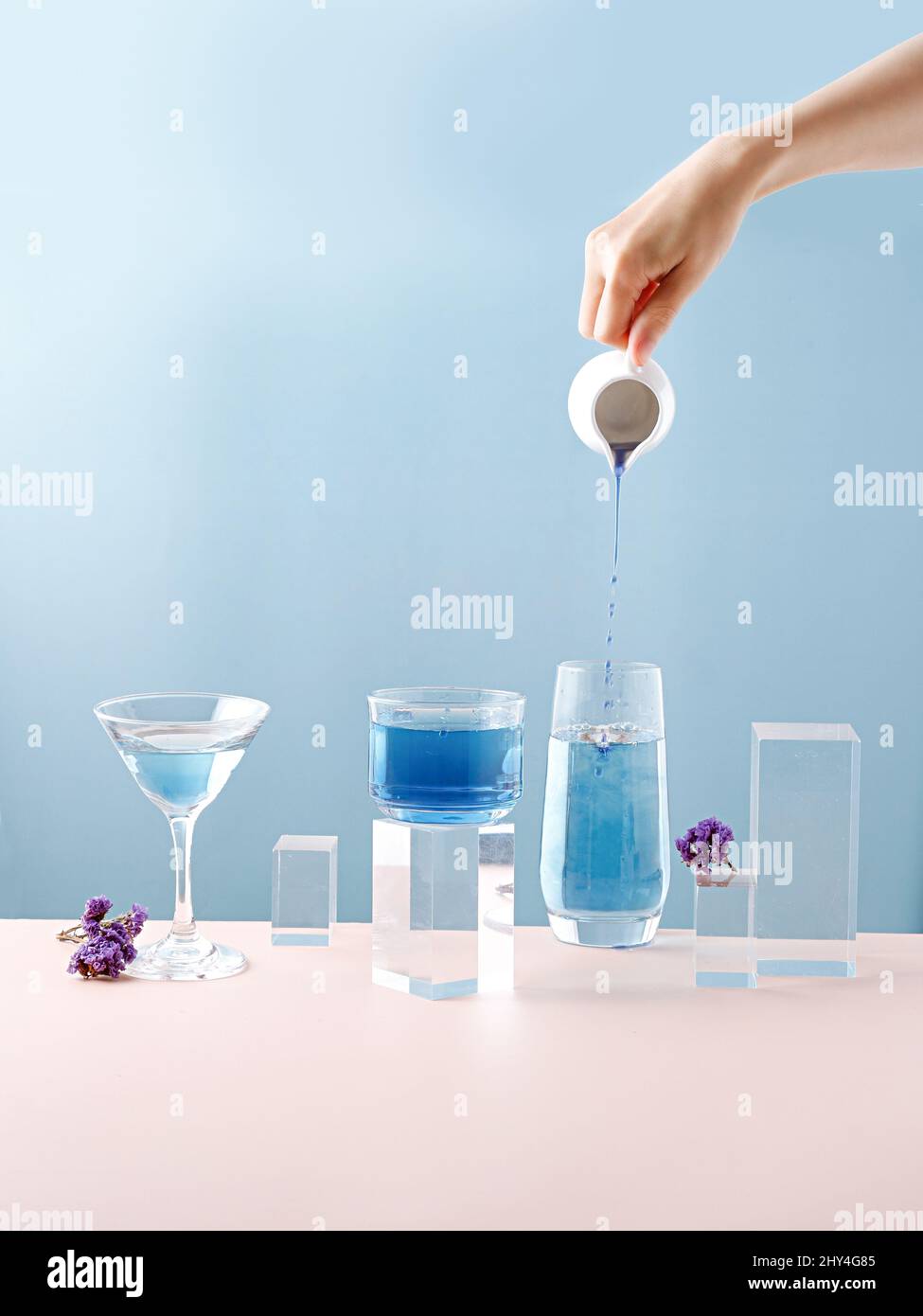 Vertical shot of the hand pouring blue liquid in the different glasses ...