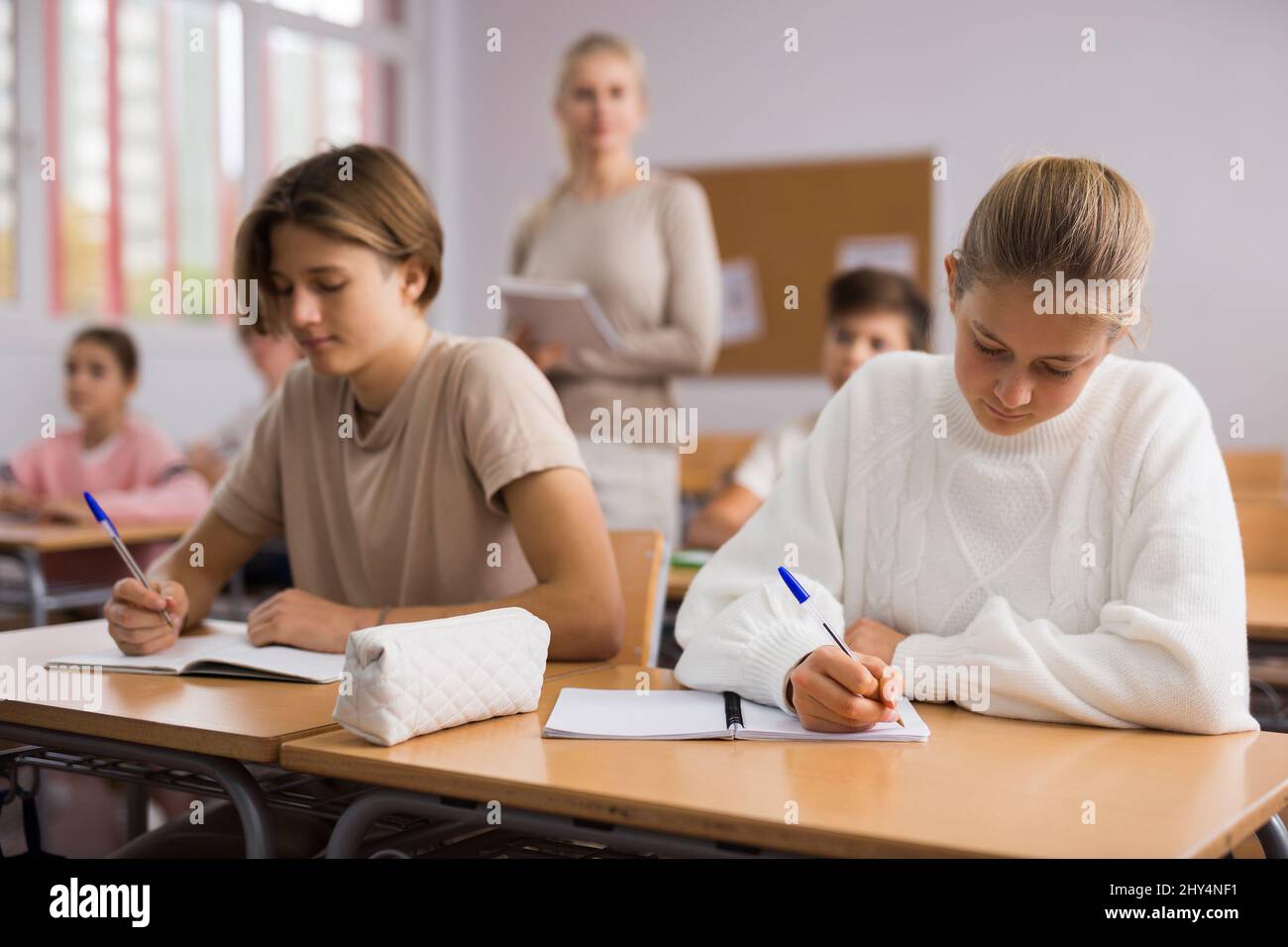 School lesson - students write down assignments while sitting at desks ...