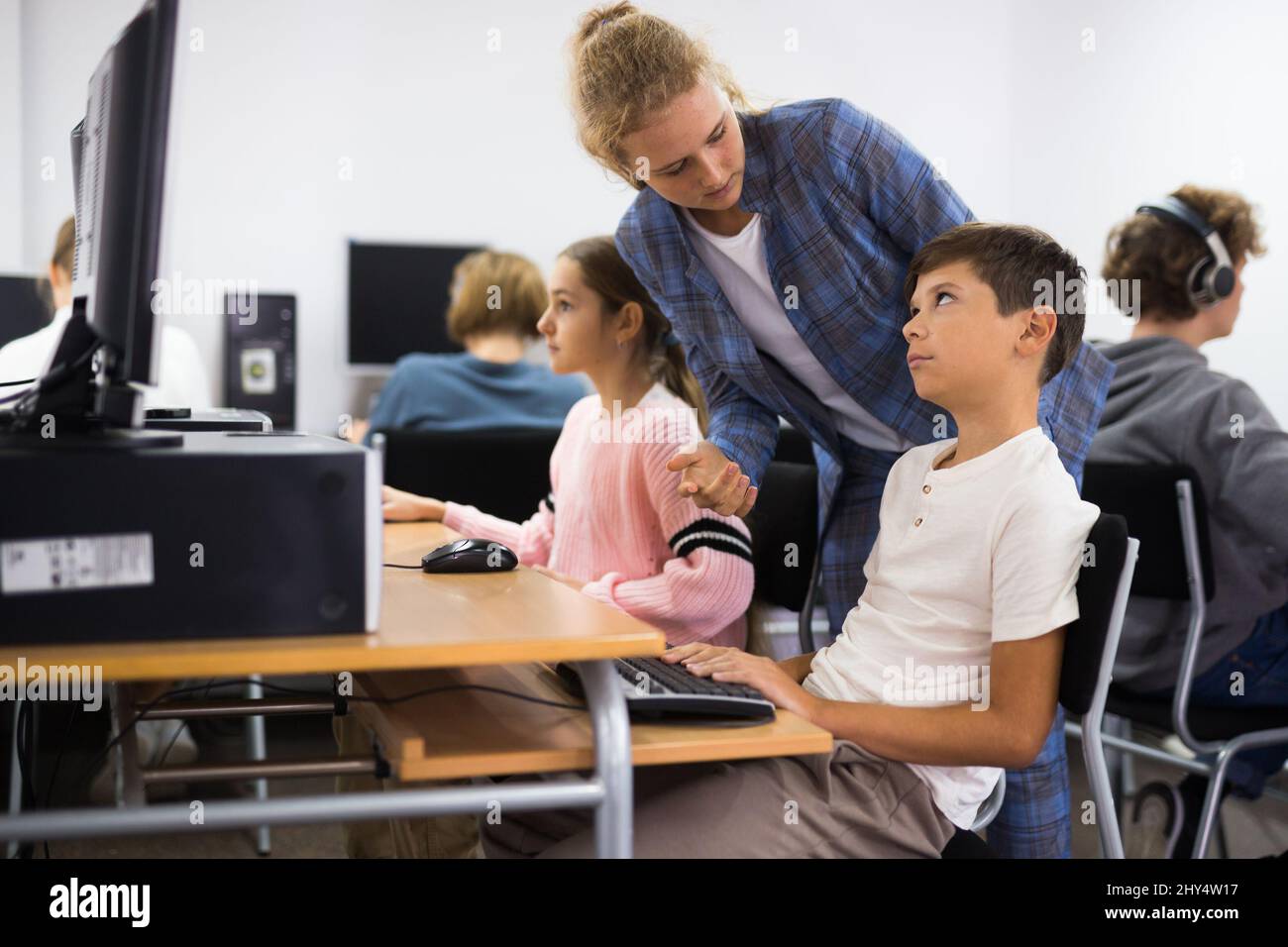 Teacher helping student with computer work Stock Photo - Alamy