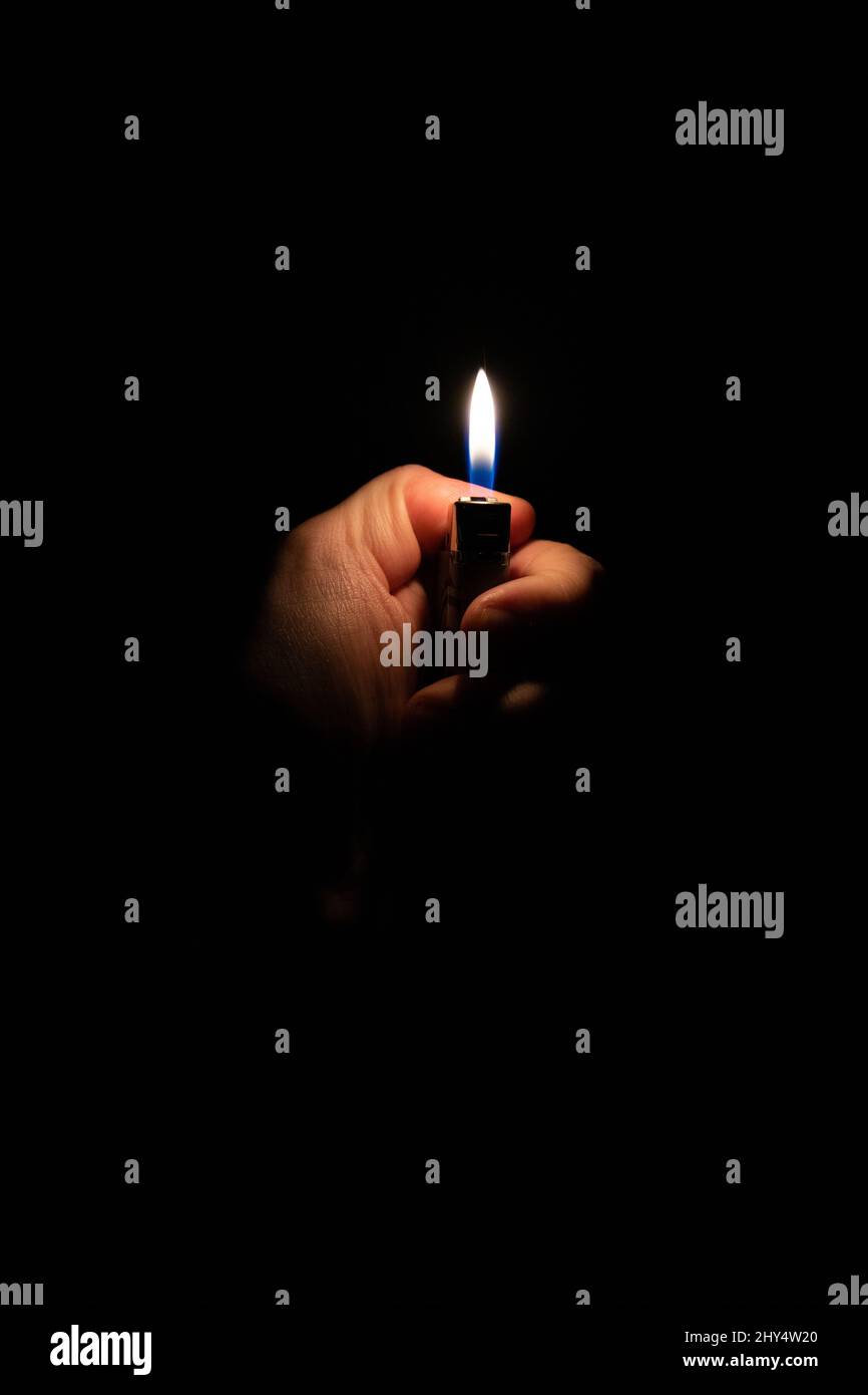Hand holding a lighter on a black background Stock Photo - Alamy