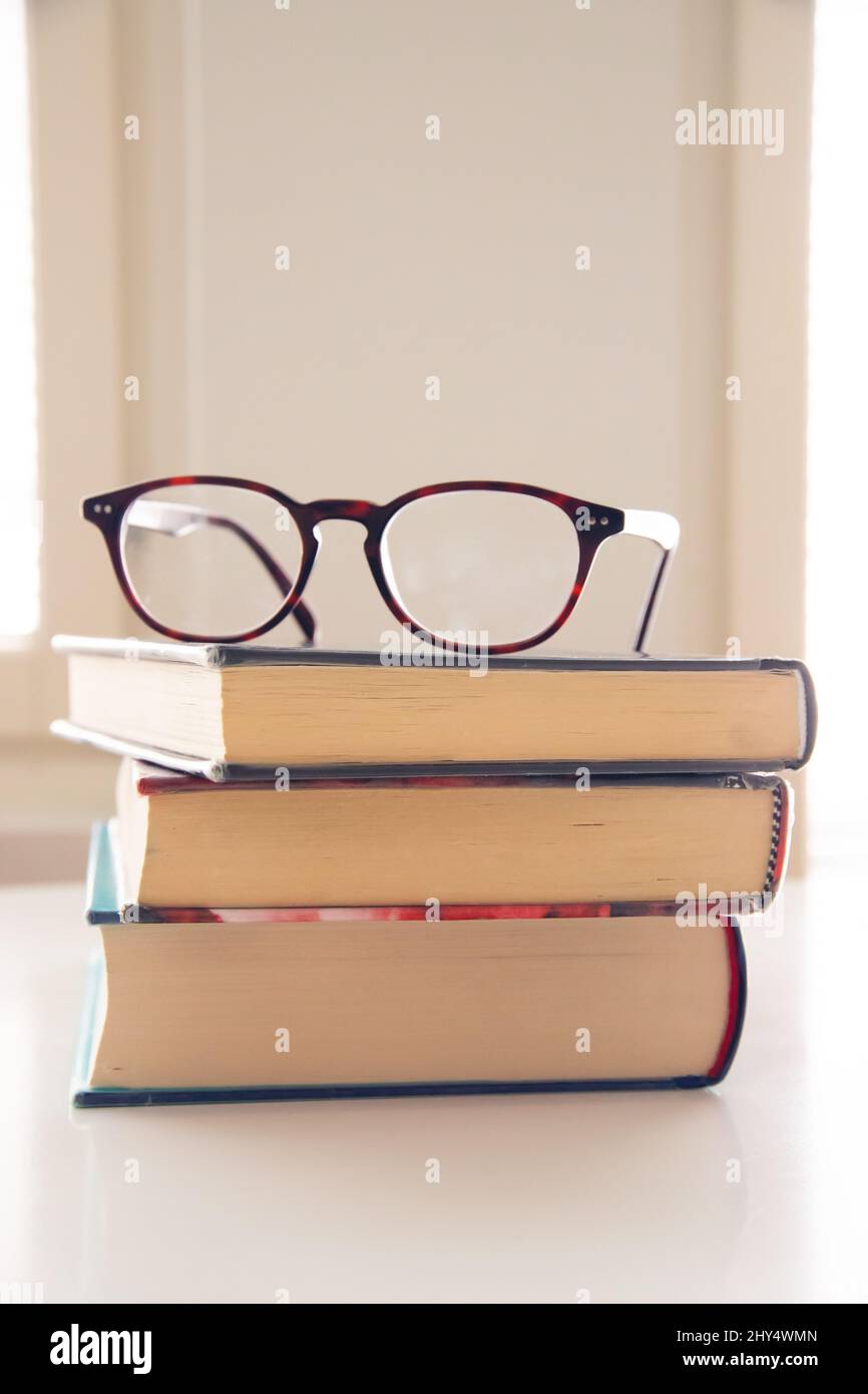 Closeup of glasses on a stack of books Stock Photo - Alamy