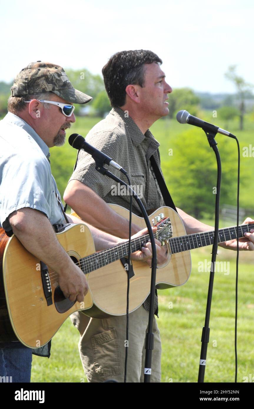Two musicians singing and playing their guitars at an outdoor event in ...