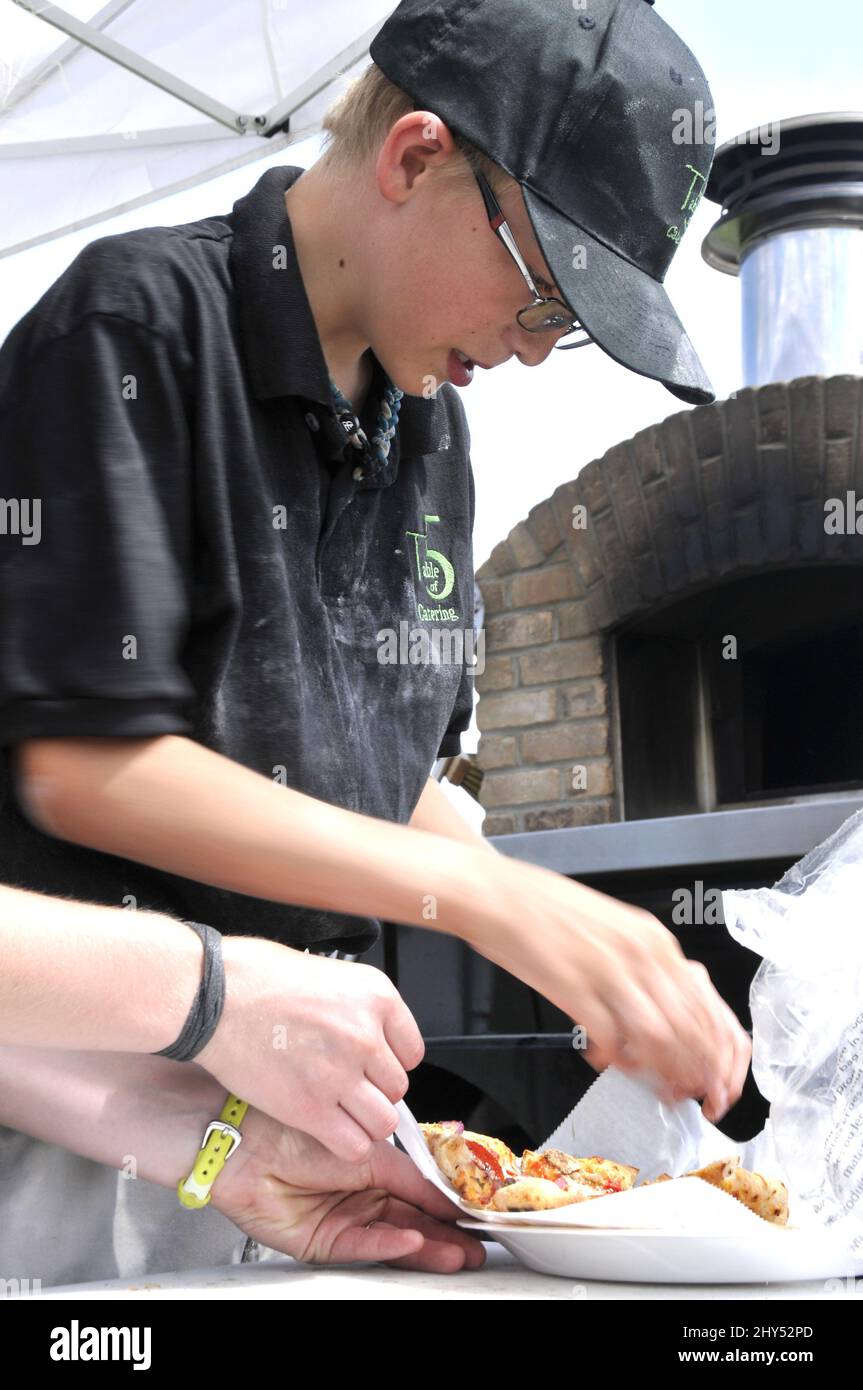 Young man prepares a pizza for baking in a wood-fired oven at an ...