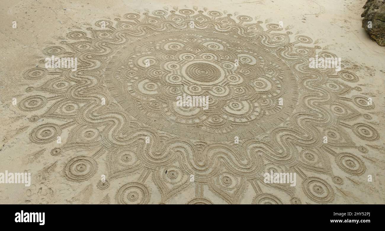 Talented street artist draws mandala in the sand at the beach Stock ...