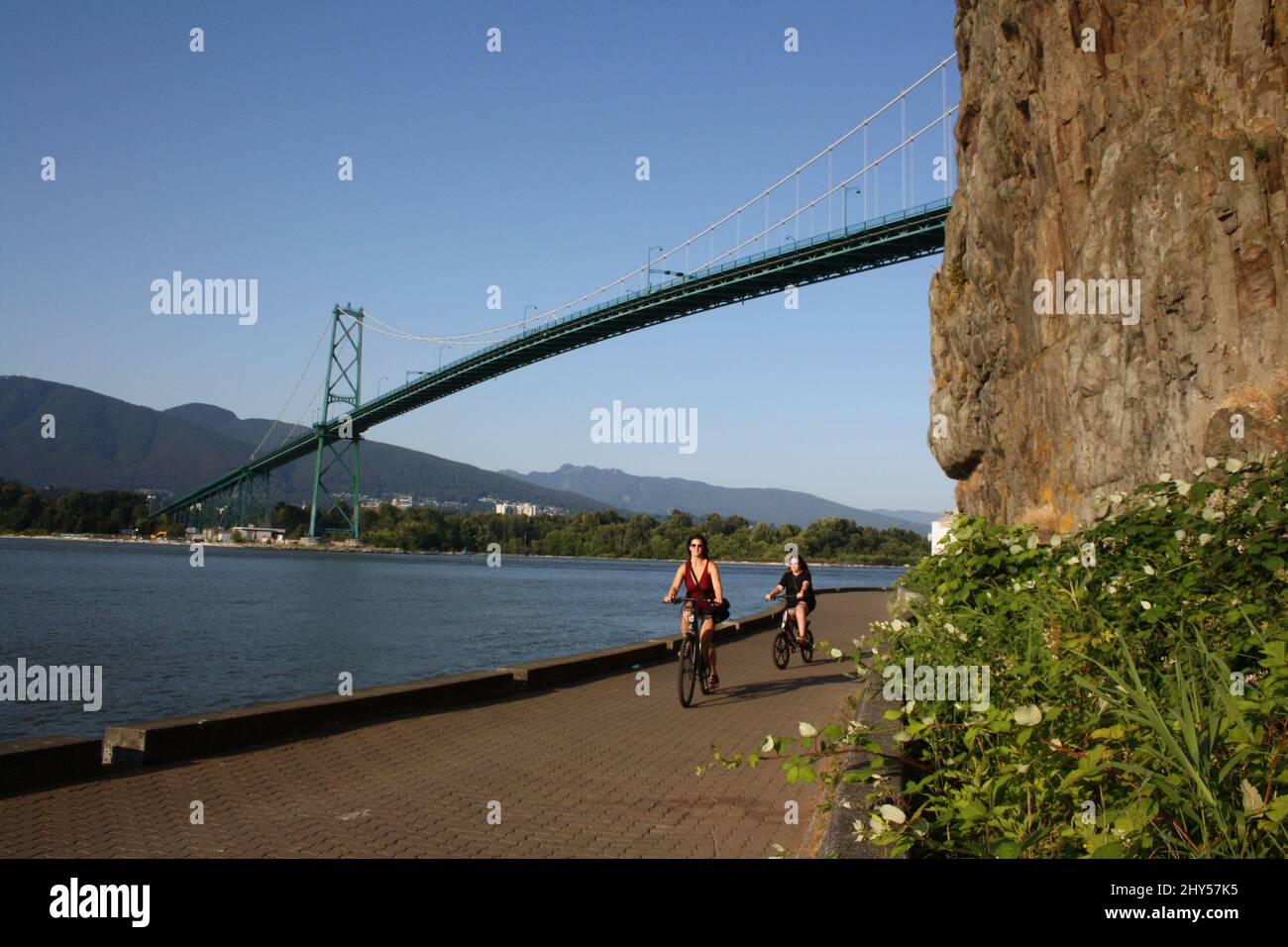 People riding bikes along the seawall under the Lions Gate Bridge in ...