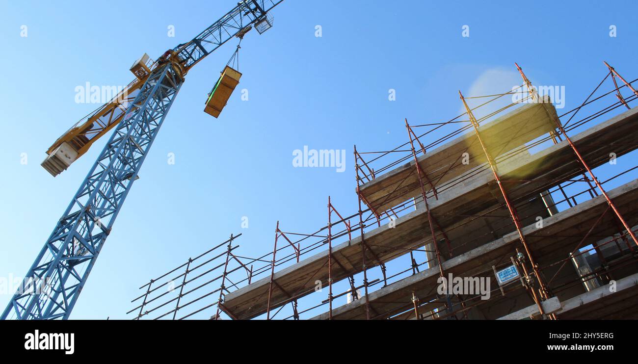 Bottom view of a crane lifting up a heavy load in the construction area ...