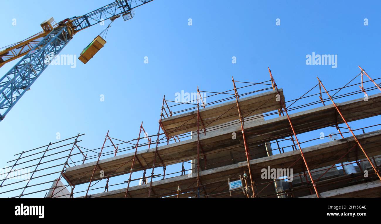 Bottom view of a crane lifting up a heavy load in the construction area ...