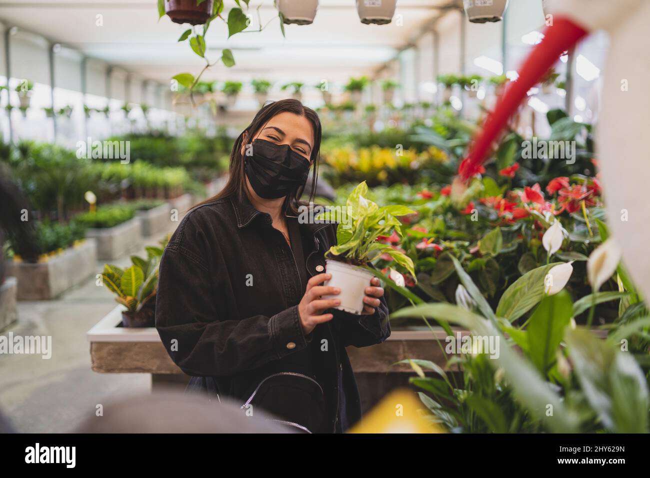 Caucasian young woman wearing a face mask looking at the exotic plants ...
