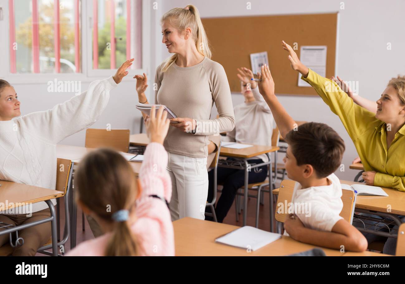 Pupils raising hands during lesson in school Stock Photo - Alamy