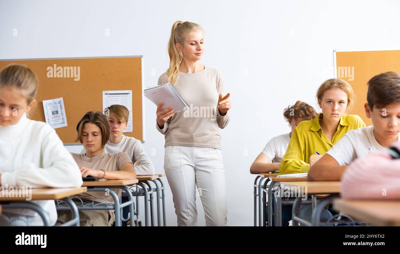 Classmates and female teacher working in groups to complete task during ...