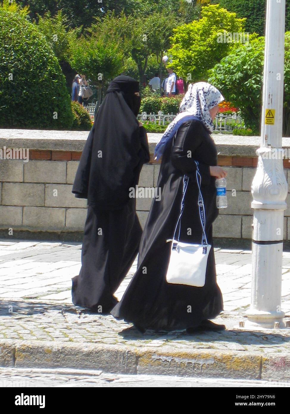 Vertical shot of Muslim women walking on the streets with fancy bags ...