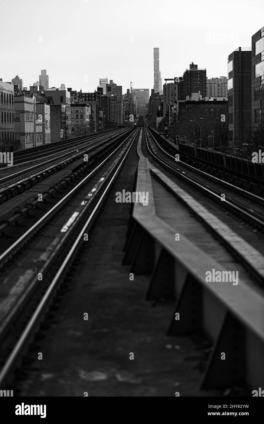 Grayscale of train tracks in the middle of buildings Stock Photo - Alamy