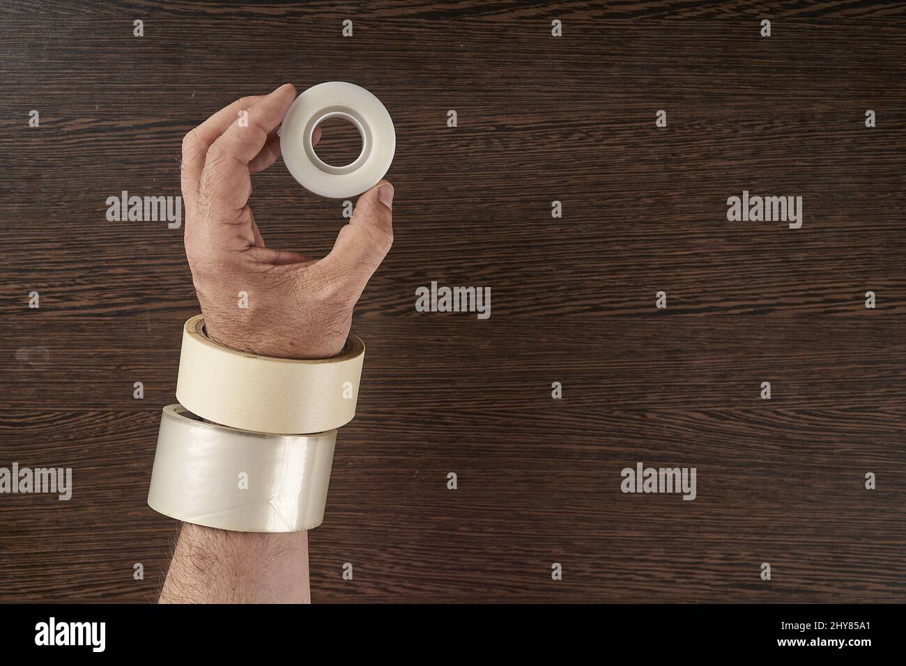 Top view of man's hand handing different types of adhesive tapes with ...