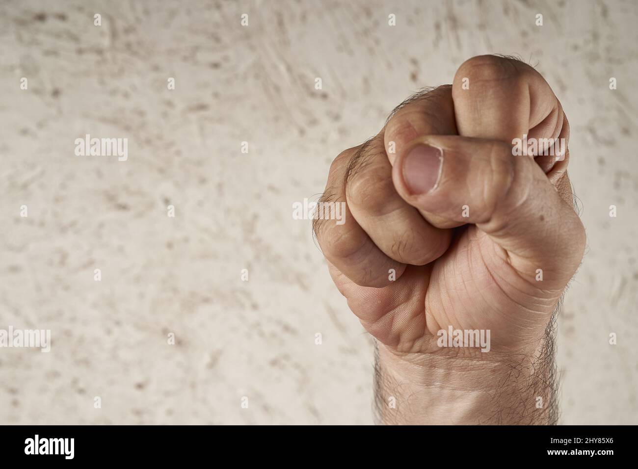 Closeup of man's hand with clenched fist strength power with light wall ...