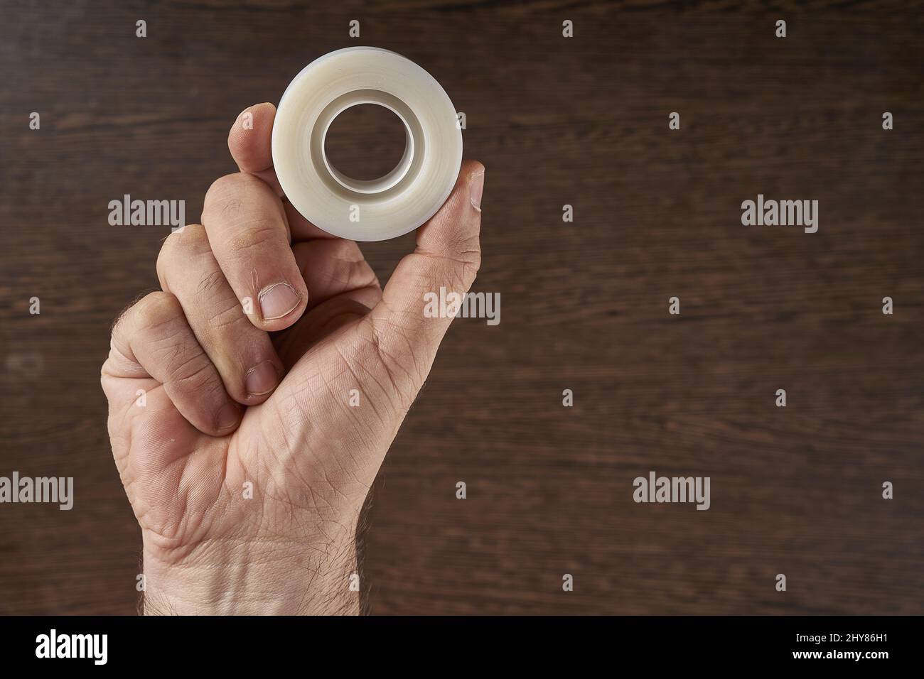 Closeup shot of man's hand handing adhesive tapes with brown background ...