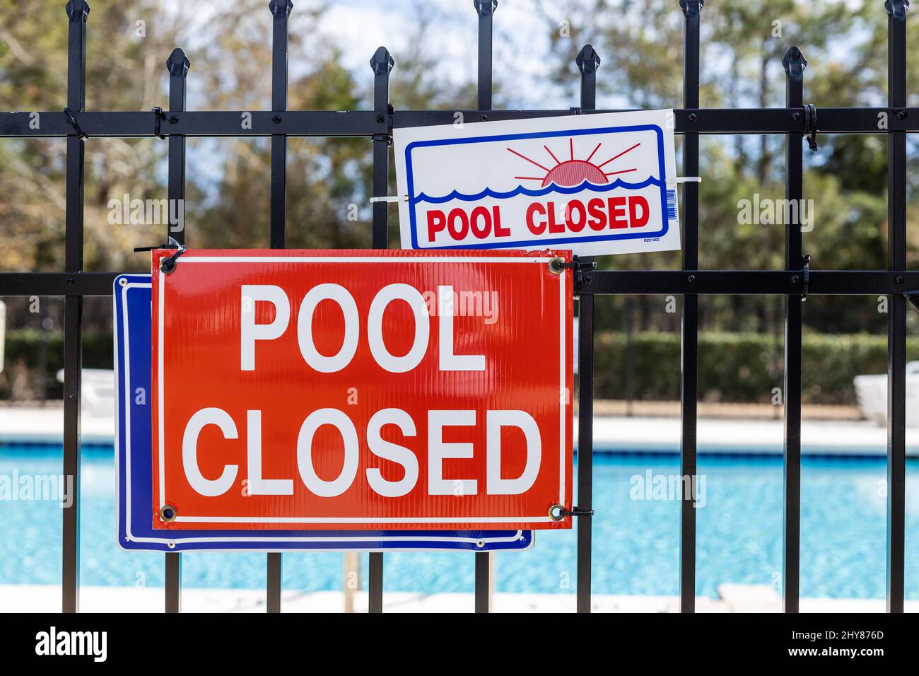 Black metal fence with two 'pool closed' signs and a swimming pool in ...