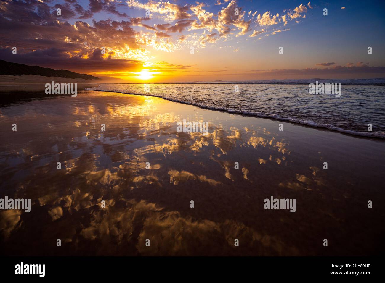 Mesmerizing seascape with cloudy sunset sky reflected on the wet sand ...