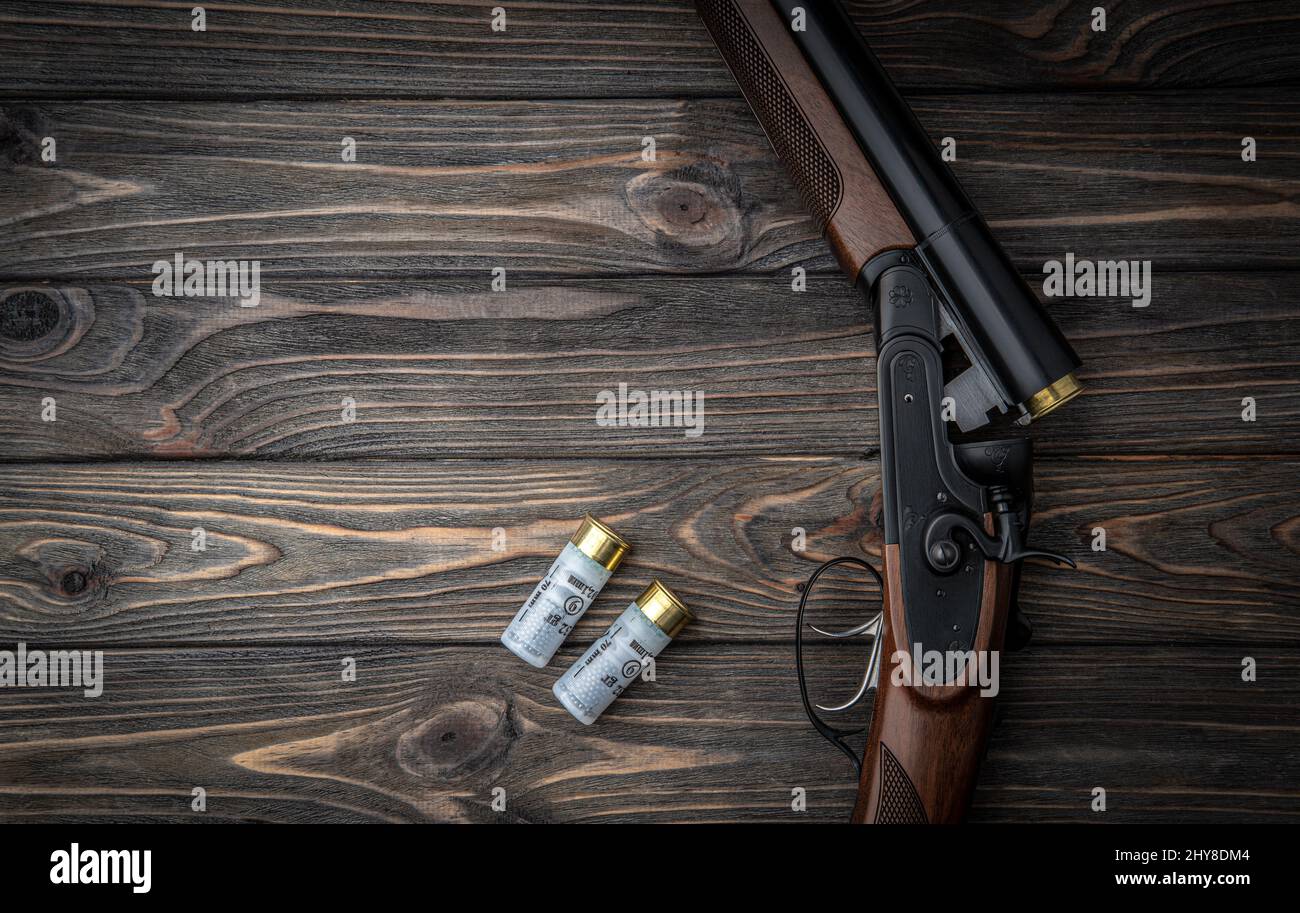 Opened double-barreled hunting rifle on a wooden table. Shotgun ammo ...