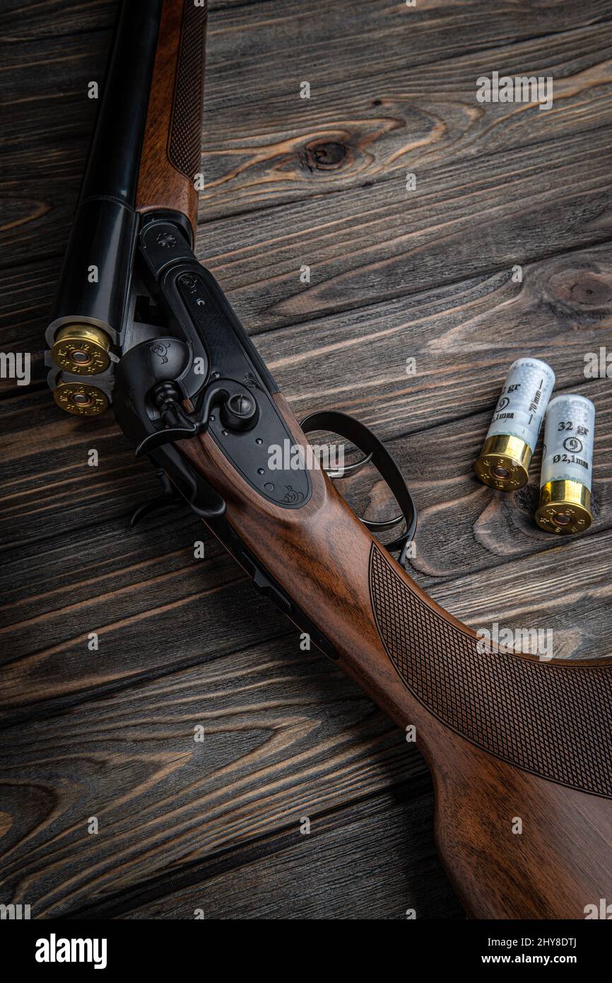 Opened double-barreled hunting rifle on a wooden table. Shotgun ammo ...