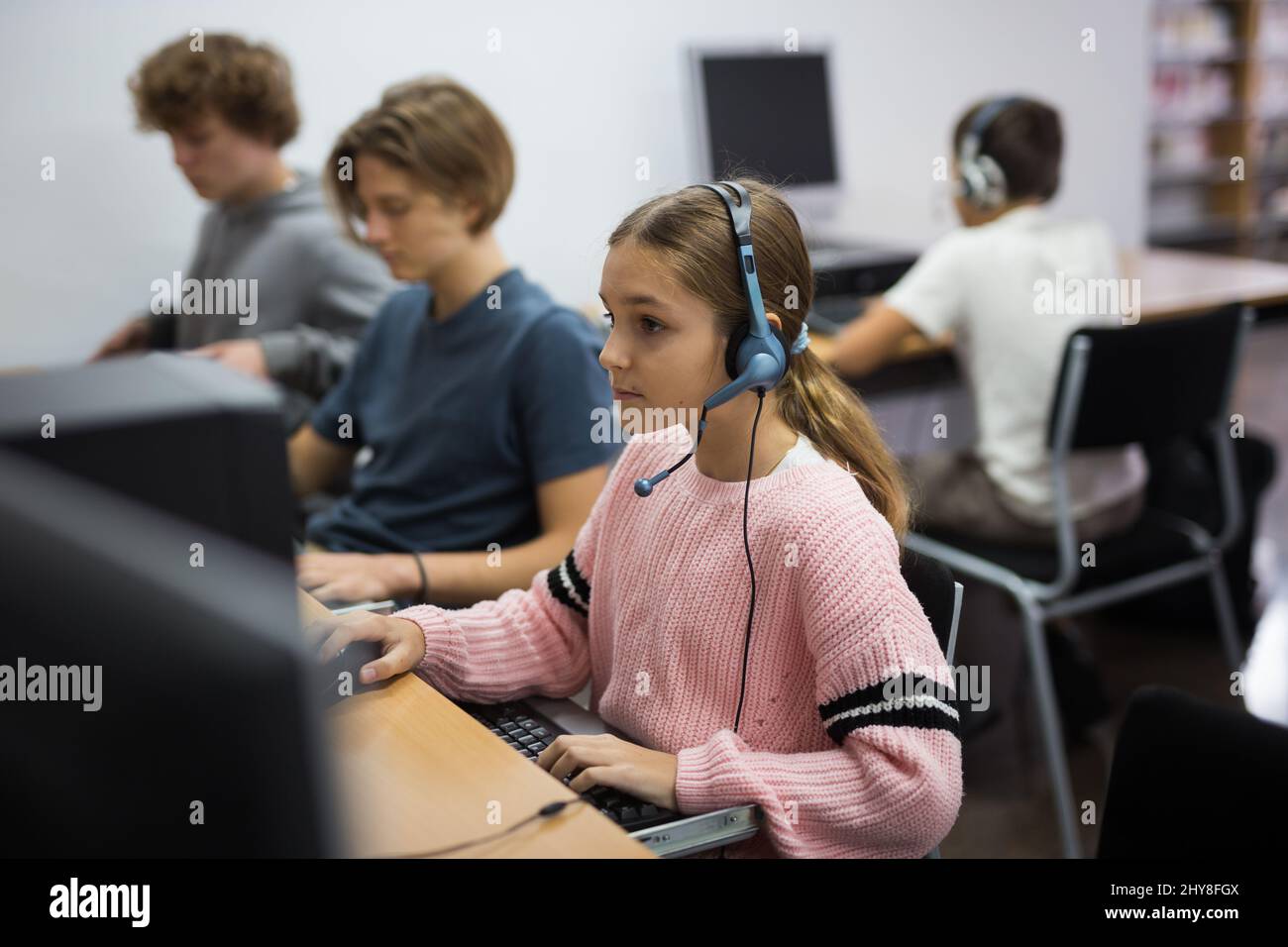 Focused ten-year-old schoolgirl wearing headphones at a computer Stock ...