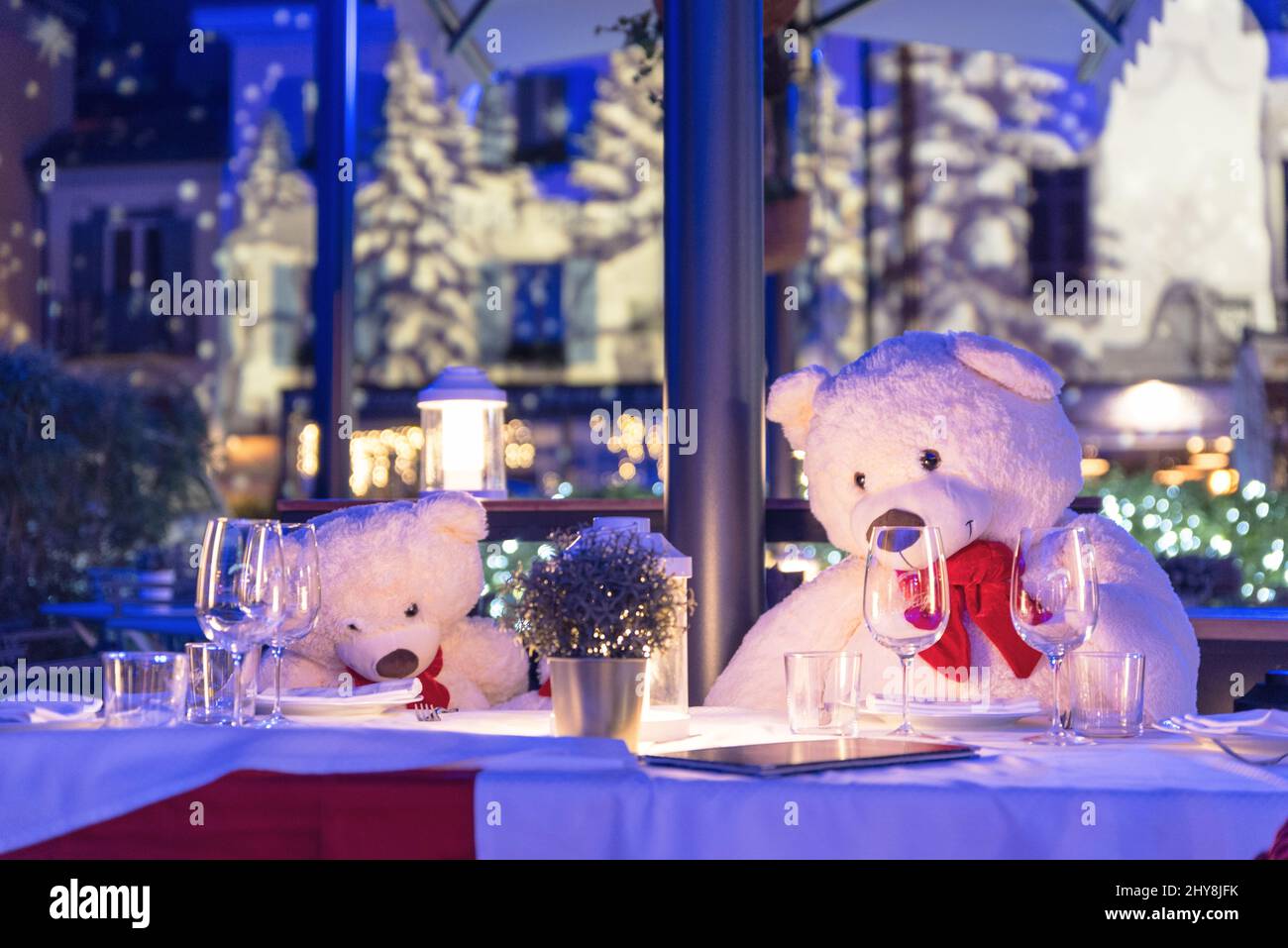 Cute shot of two white plushie bears with red bows sitting around a ...