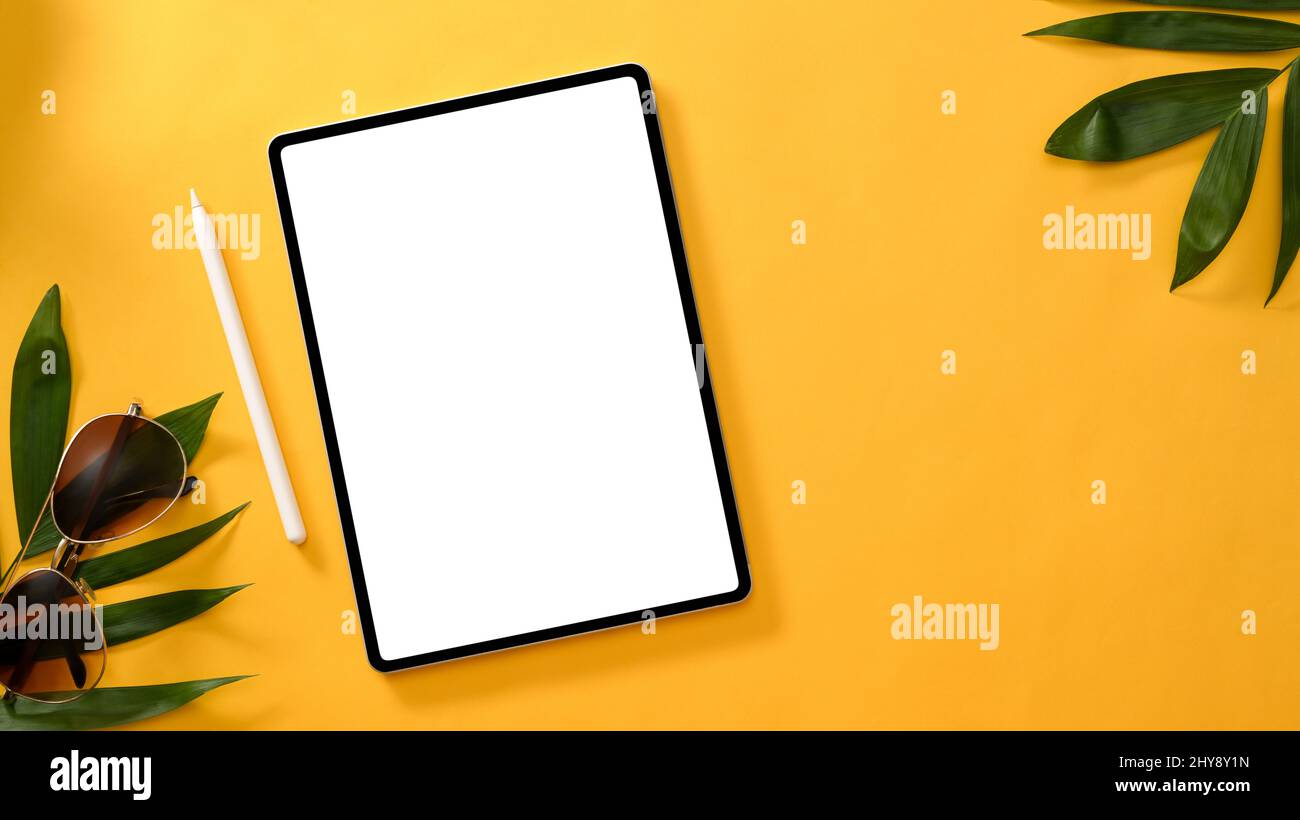 Creative yellow workspace background with portable tablet touchpad ...