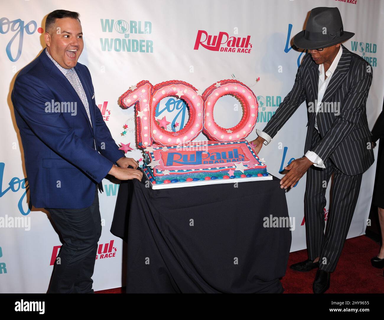 Ross Matthews and RuPaul stand next to a cake celebrating 100 episodes ...