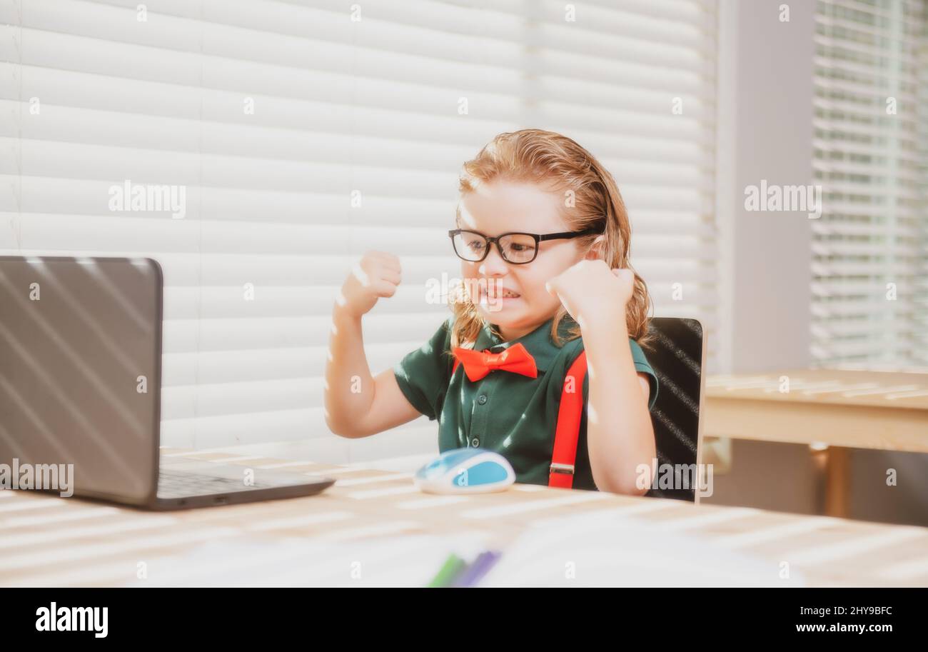 Excited schoolboy using a laptop and study online lesson. Pupil at ...