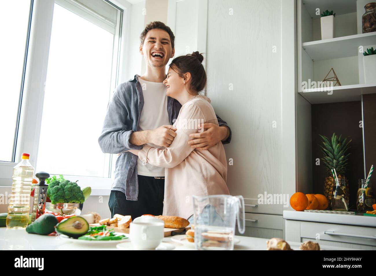 Smiling man hugging caucasian woman standing in the kitchen during the ...