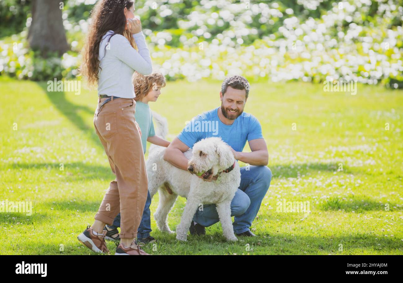 Happy family playing with dog resting together on the green grass ...