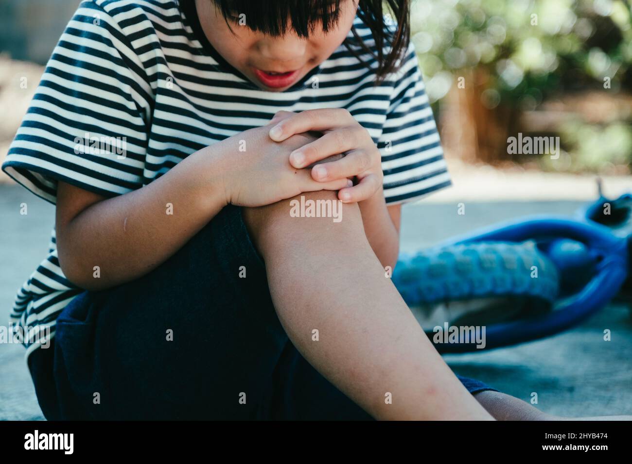 Sad little girl sitting on the ground after falling off her bike at ...