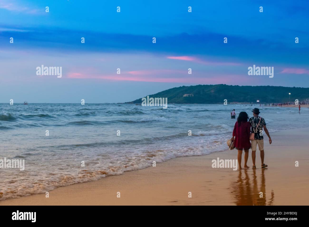 Back view of a couple walking on the Bago beach at sunset Stock Photo ...