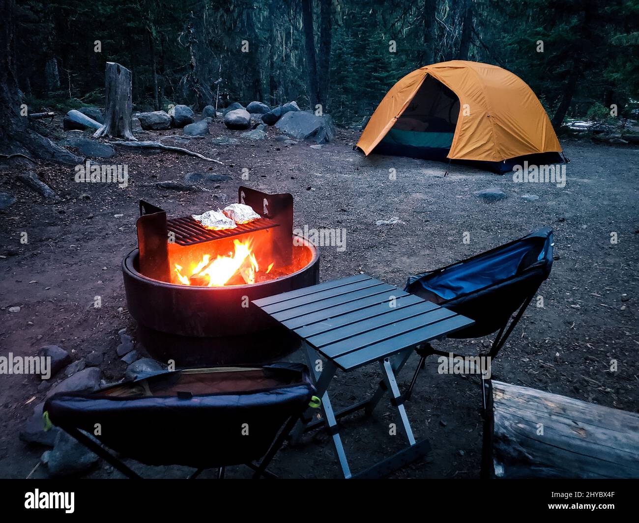 Camping site with tents and a burning grill fire in a forest Stock ...