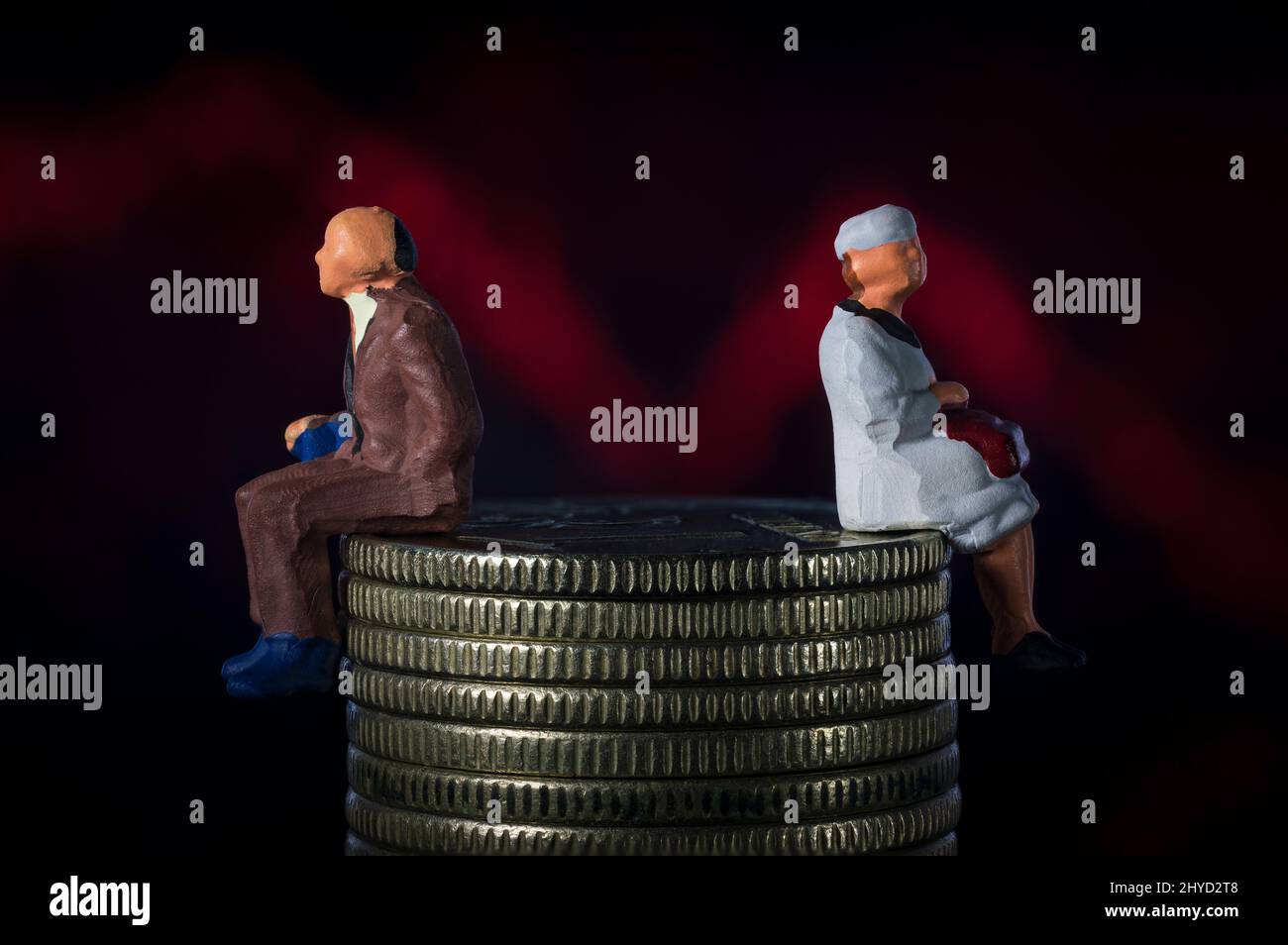 Miniature people. Senior old couple sitting on stack of coins. Red line ...