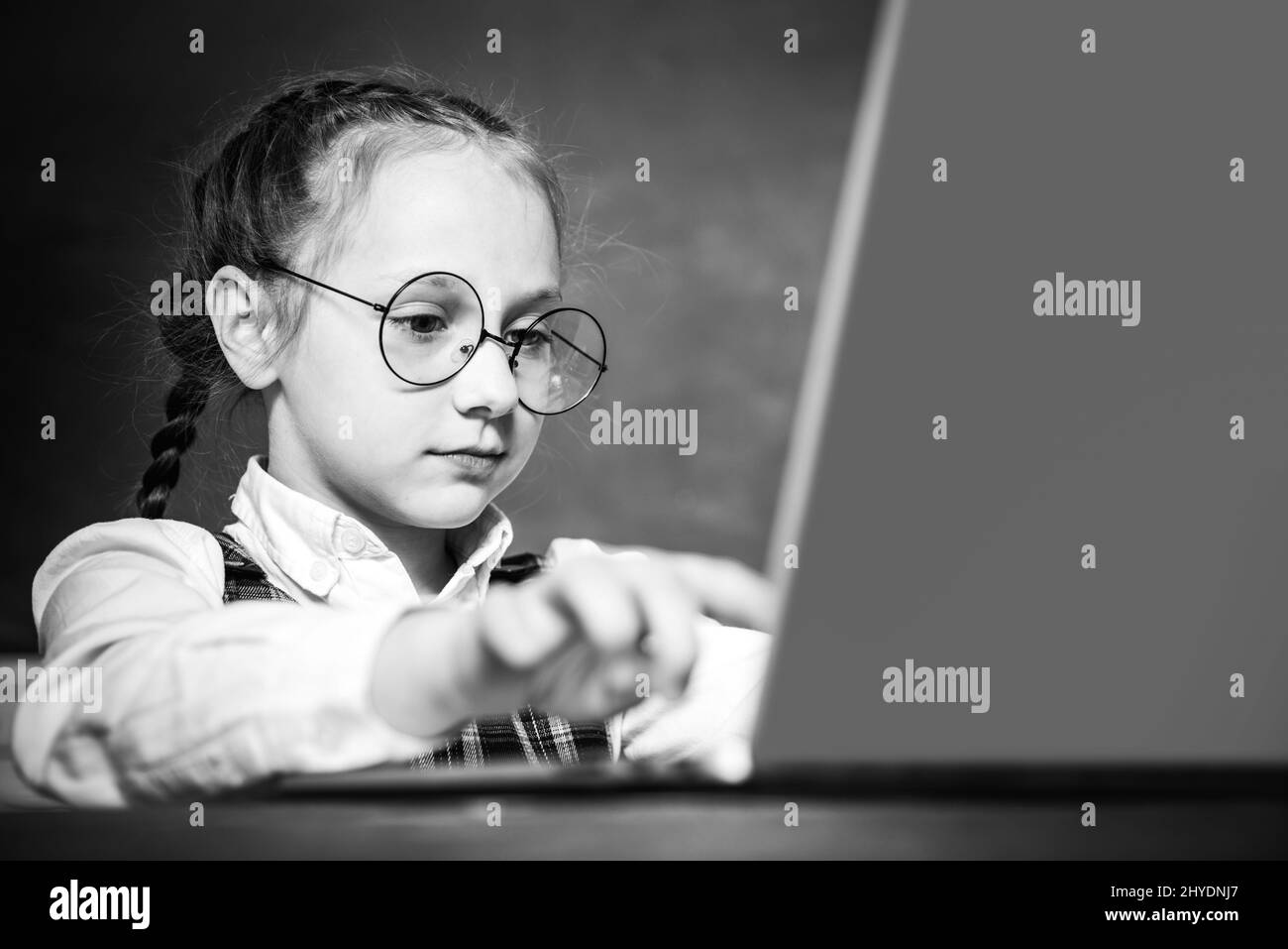 Pupil working on laptop computer over blackboard background. Child near ...