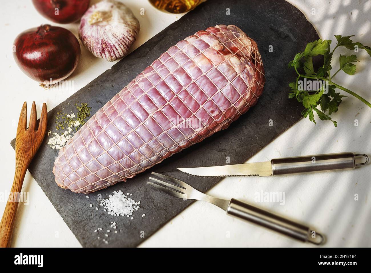 Top view shot of raw Roast Beef in the net on a cutting board with ...