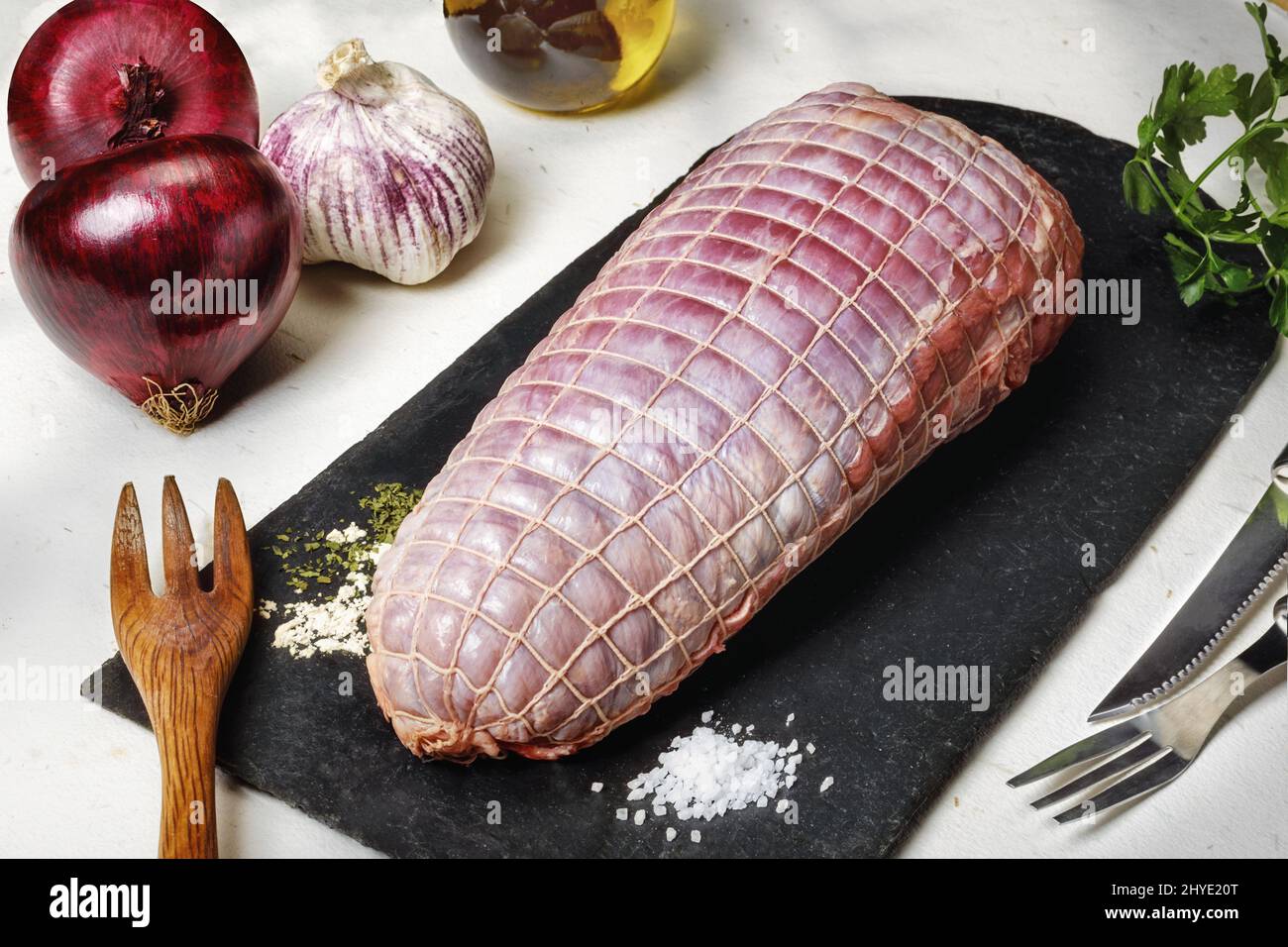 Closeup shot of raw Roast Beef in the net on a cutting board with ...