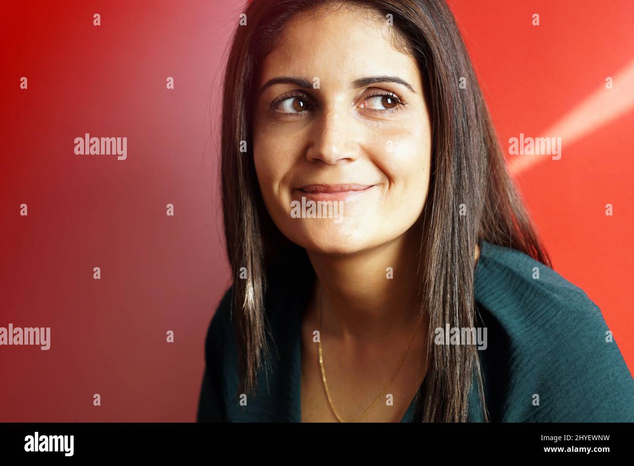 Portrait of a Hispanic woman looking right in a red background Stock ...