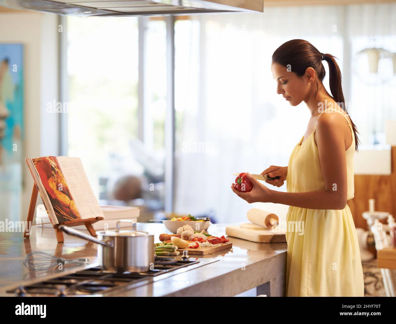 Cooking up a storm. A young woman cooking from a recipe Stock Photo - Alamy