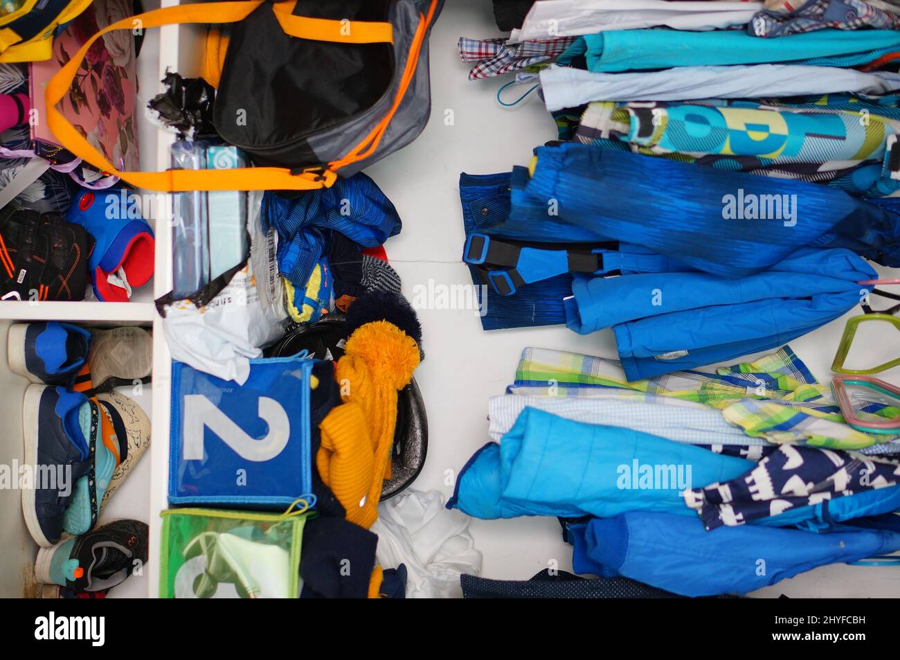 Closeup of an open messy kids wardrobe with hanging jackets and other ...