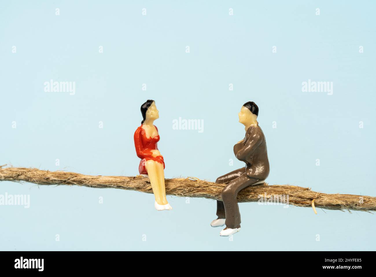 A man and a woman miniature models sitting on a rope Stock Photo - Alamy