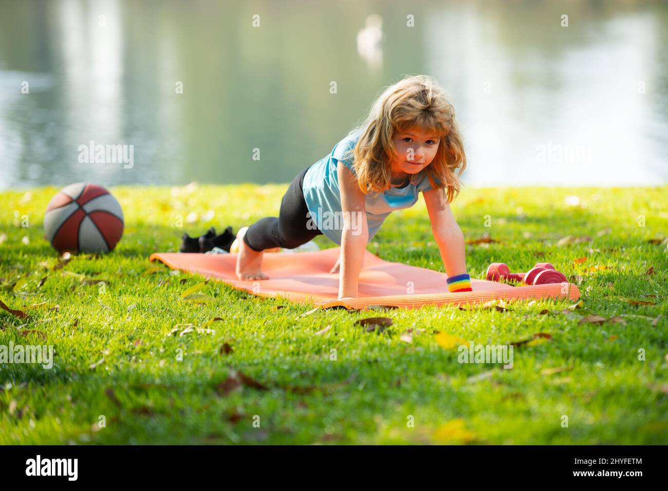 Child doing gymnastic exercises, sportive kid doing push ups on fitness ...