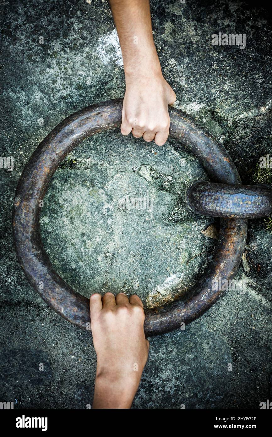 Vertical wallpaper of two hands pulling a giant iron ring pull from the ...