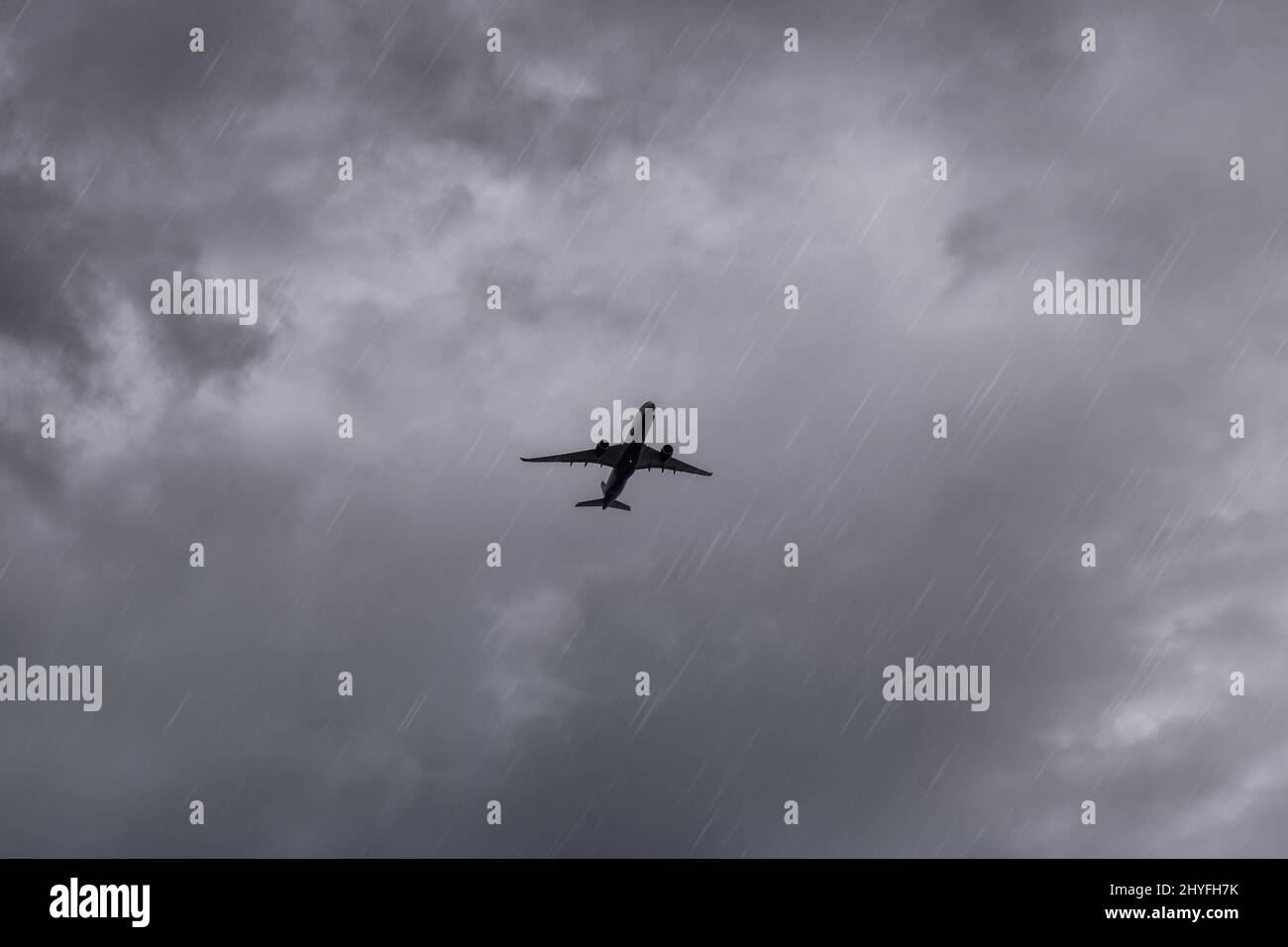 Grayscale shot of a plane flying in the sky in rainy weather Stock ...