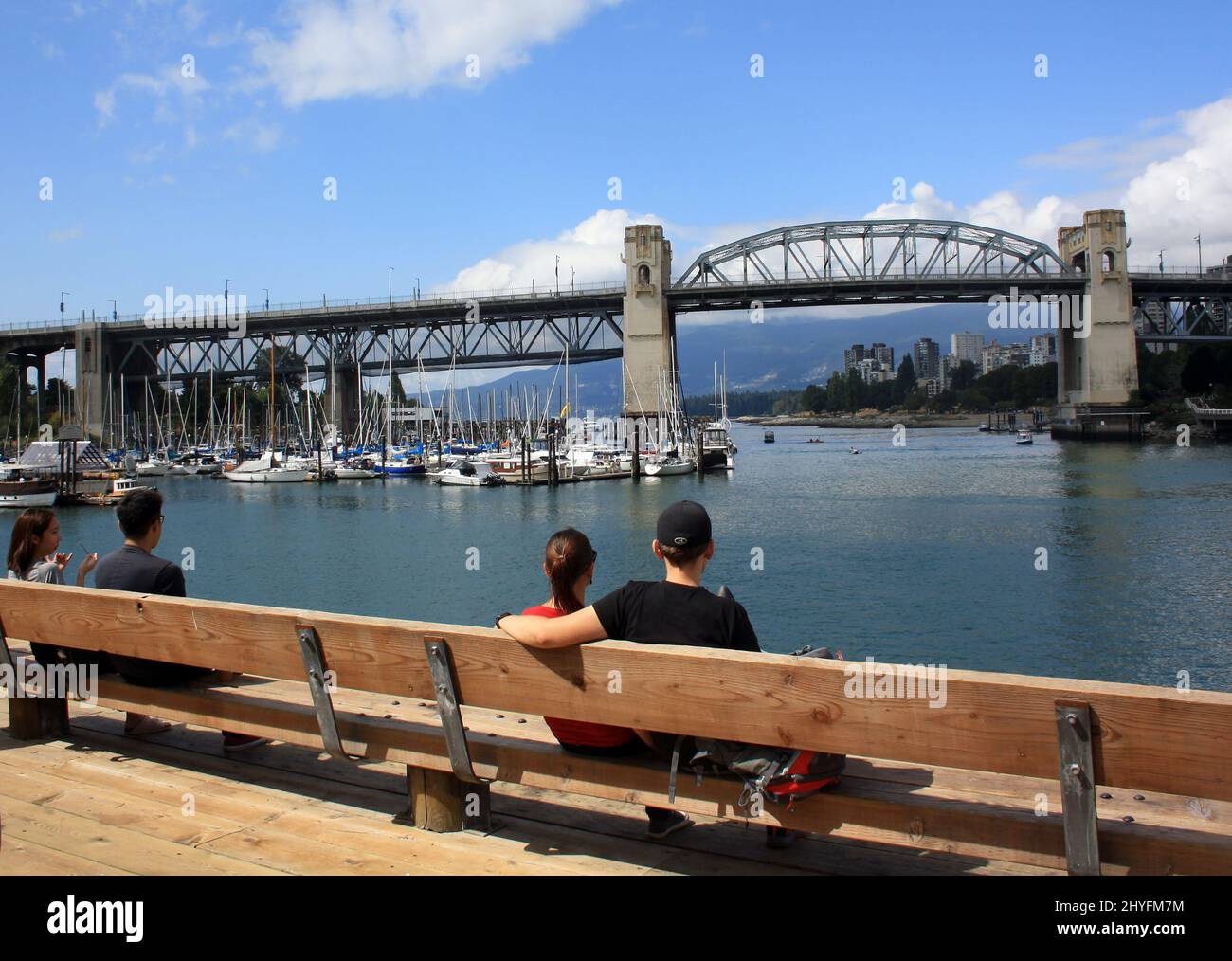 Group of people sitting on the bench at Granville Island, with Burrard ...