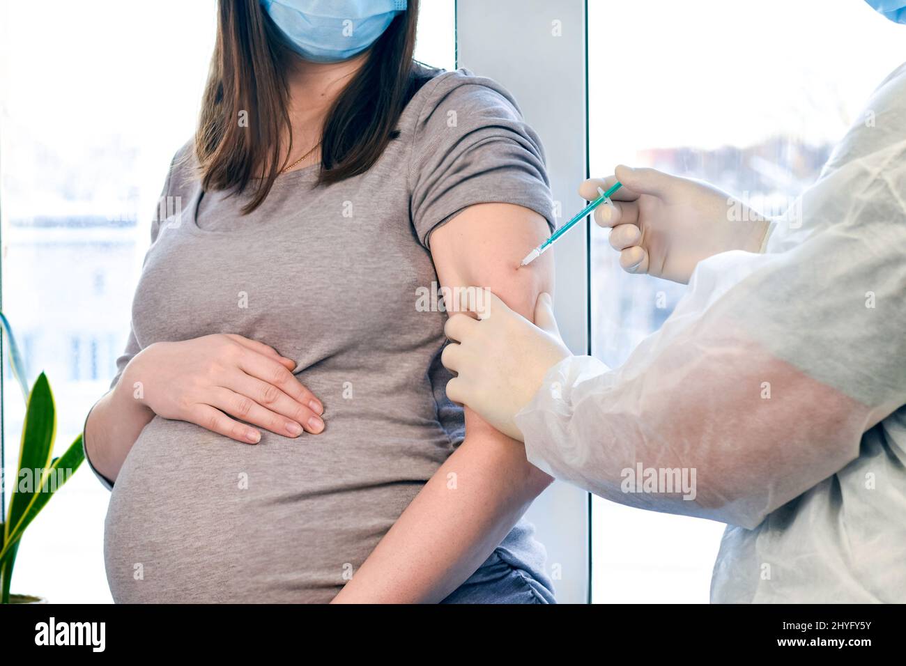 Doctor giving COVID-19 coronavirus vaccine injection to pregnant woman ...