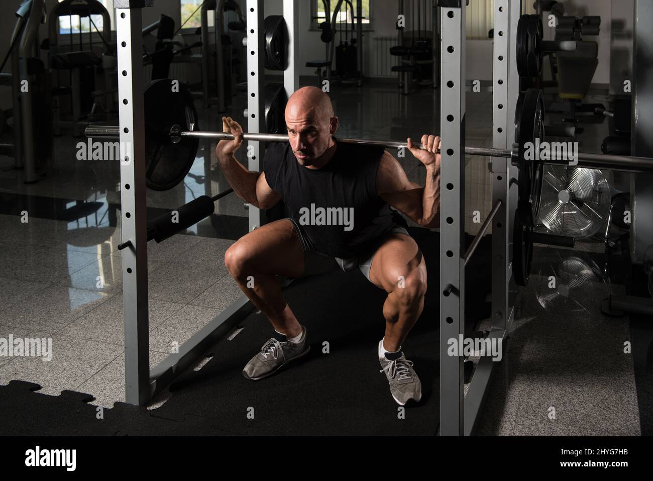 Healthy Fitness Man Working Out Legs With Barbell In A Gym - Front ...