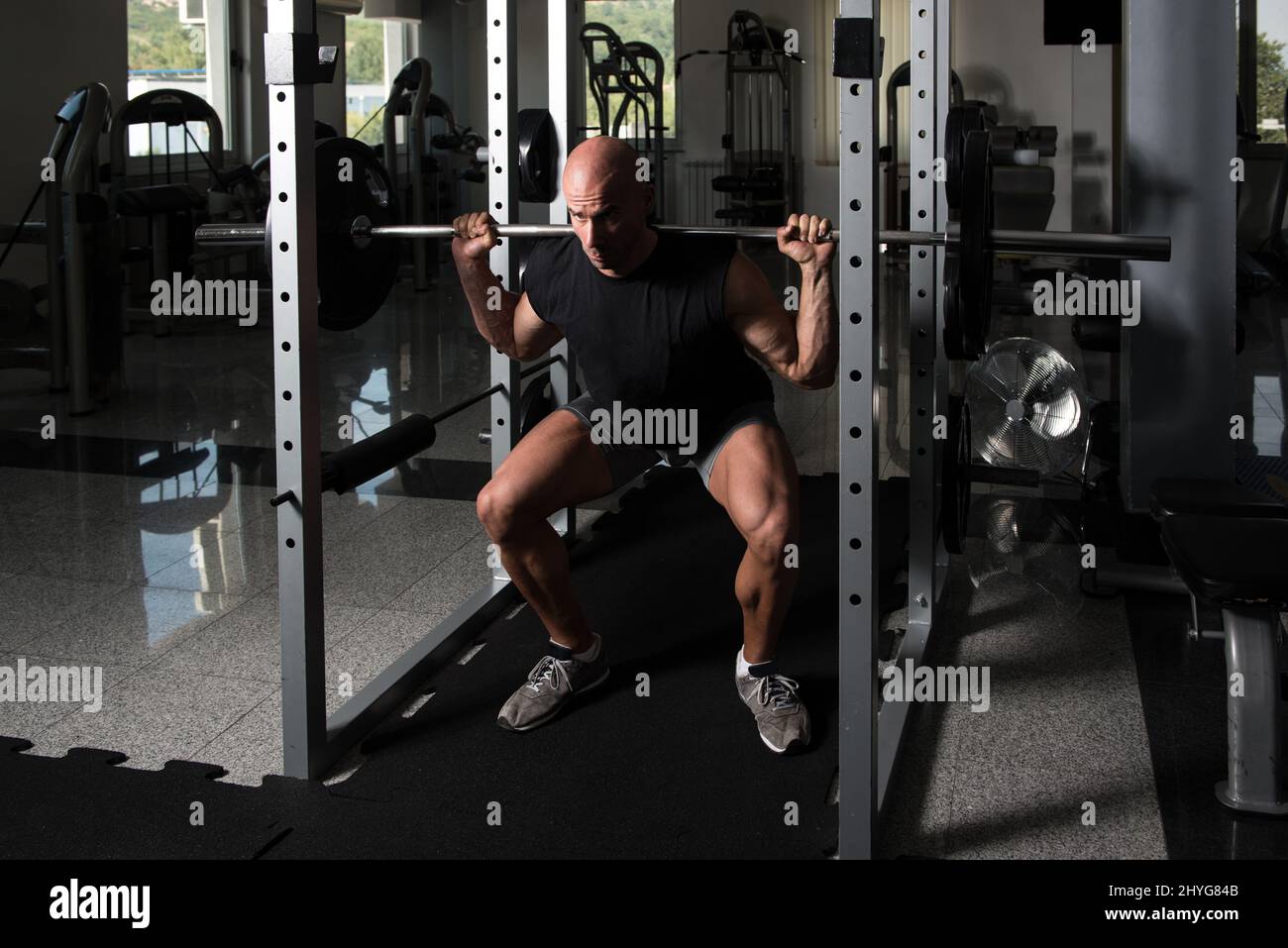 Healthy Fitness Man Working Out Legs With Barbell In A Gym - Front ...