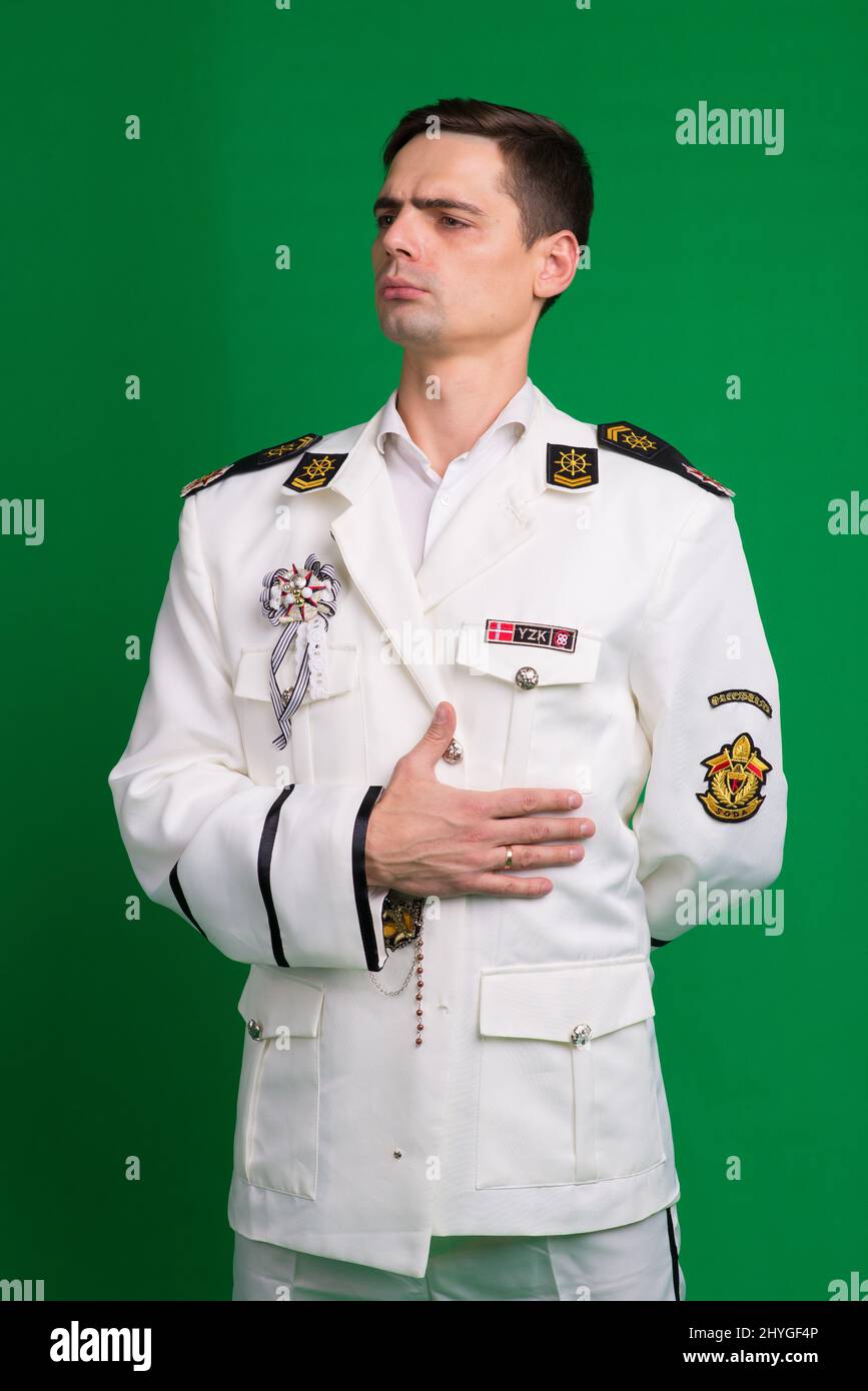 A marine captain wearing a white suit, standing half-turned, isolated ...