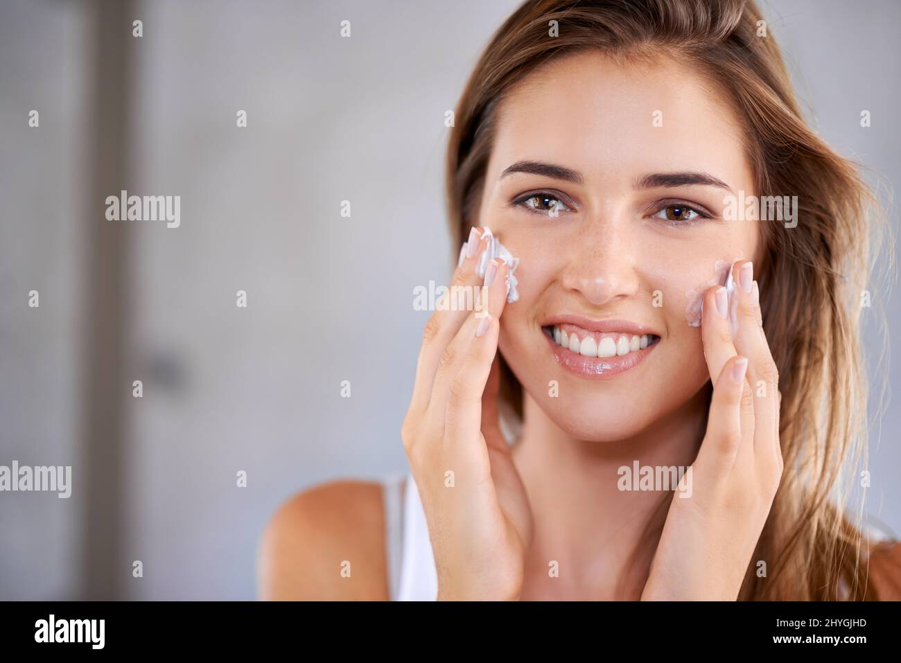 complete skin care. Shot of a beautiful woman applying moisturizer to ...